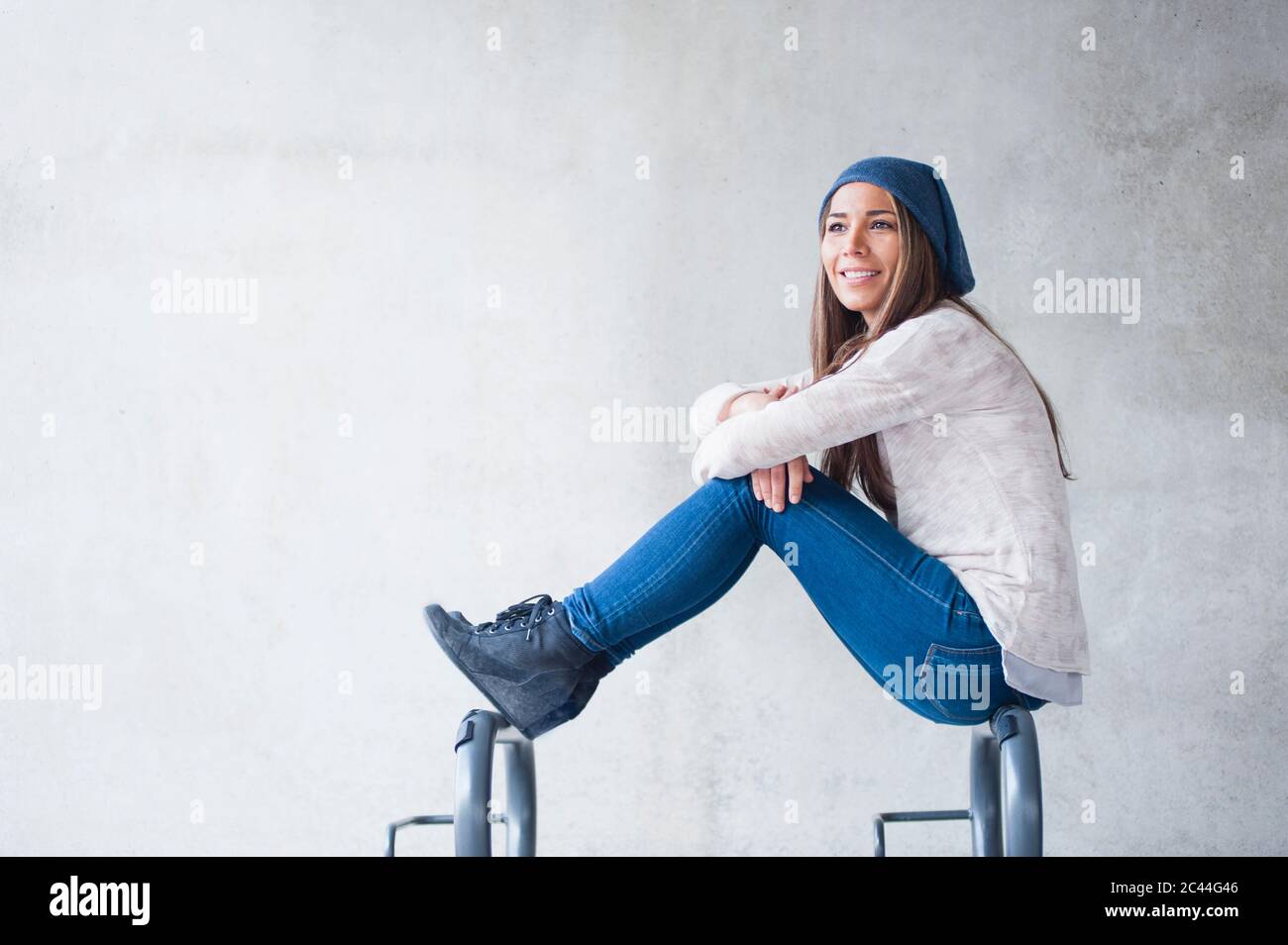 Thoughtful woman sitting on metallic rails against gray wall Stock ...