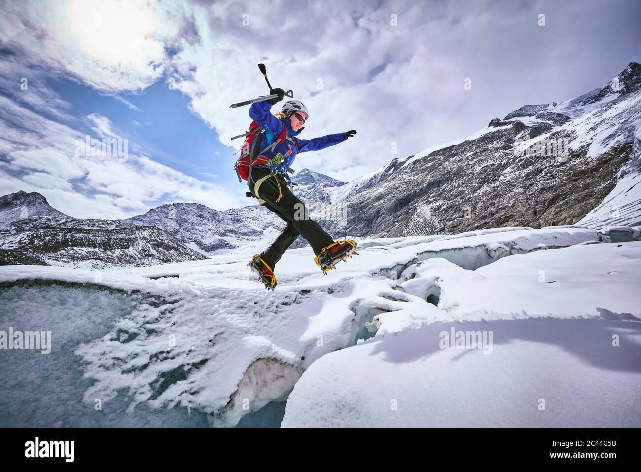 Female mountaineer jumping over crevasse, Glacier Grossvendediger ...