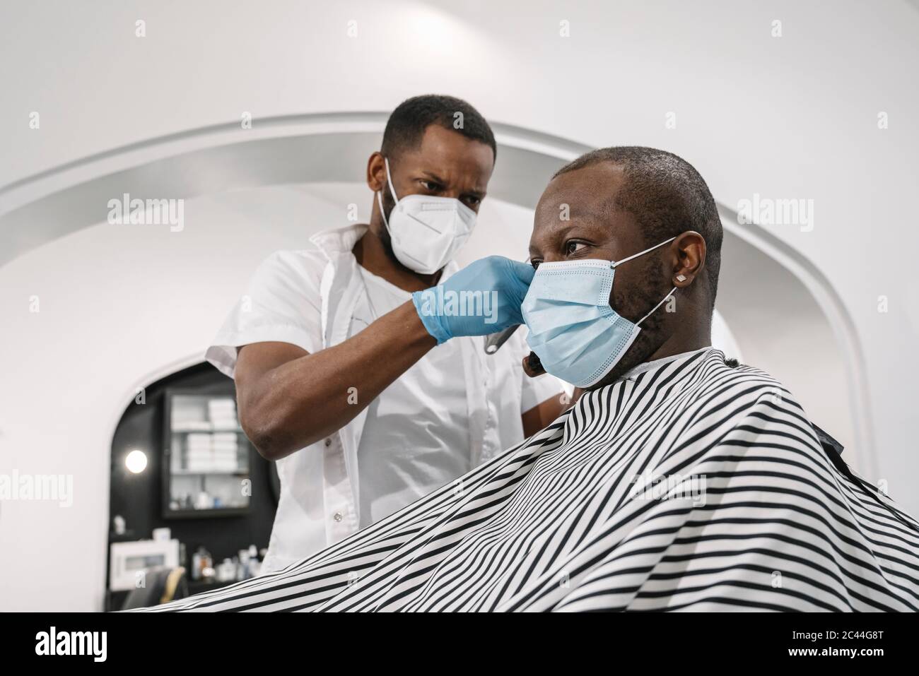 Barber wearing surgical mask and gloves cutting hair of customer Stock ...