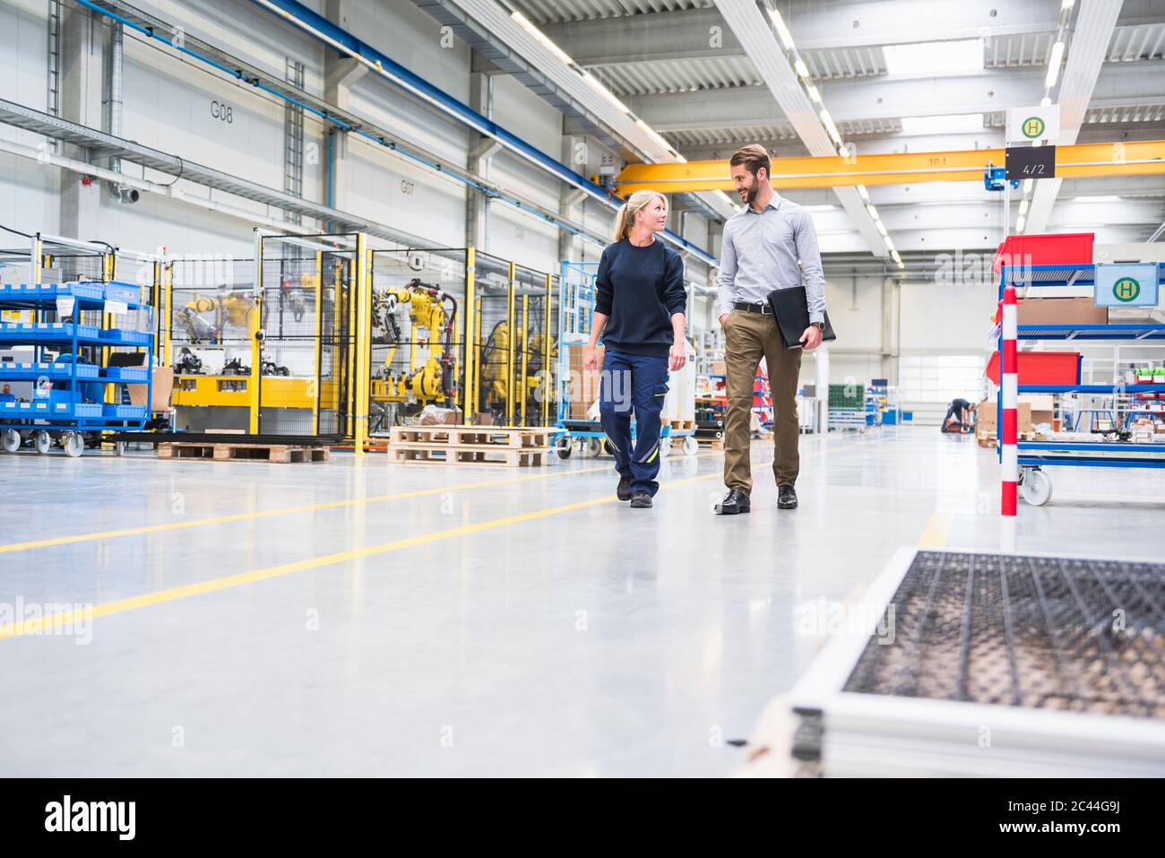 Man and a woman walking and talking in a factory Stock Photo - Alamy