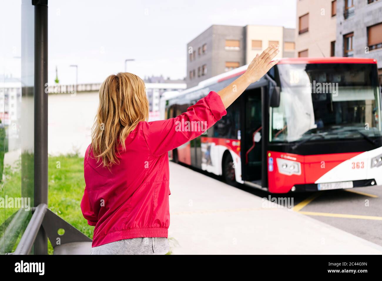 Woman stopping bus at bus stop Stock Photo - Alamy