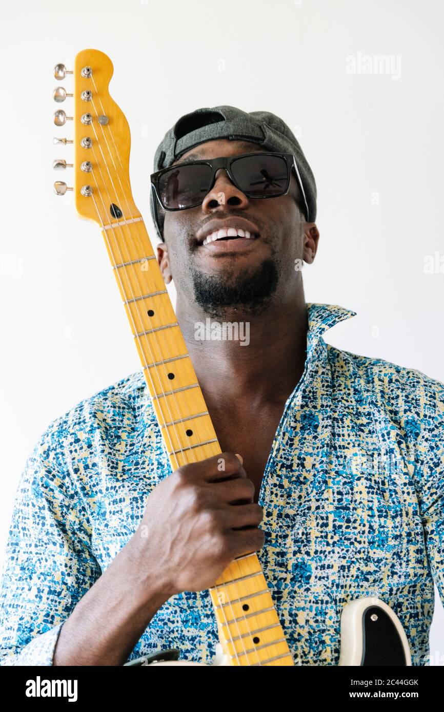Portrait of confident male guitarist holding guitar against white ...