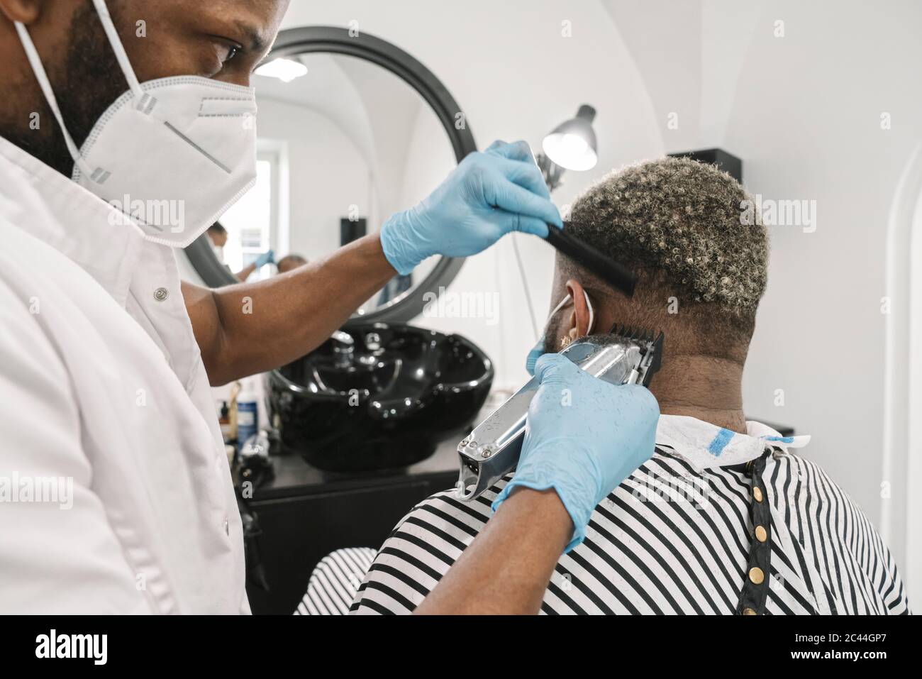 Barber wearing surgical mask and gloves shaving hair of customer Stock ...