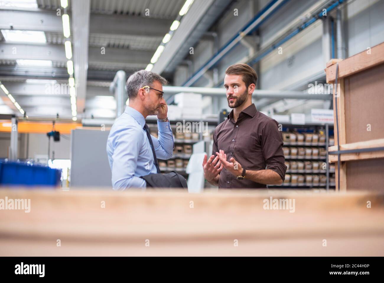 Two businessmen talking in a factory Stock Photo - Alamy