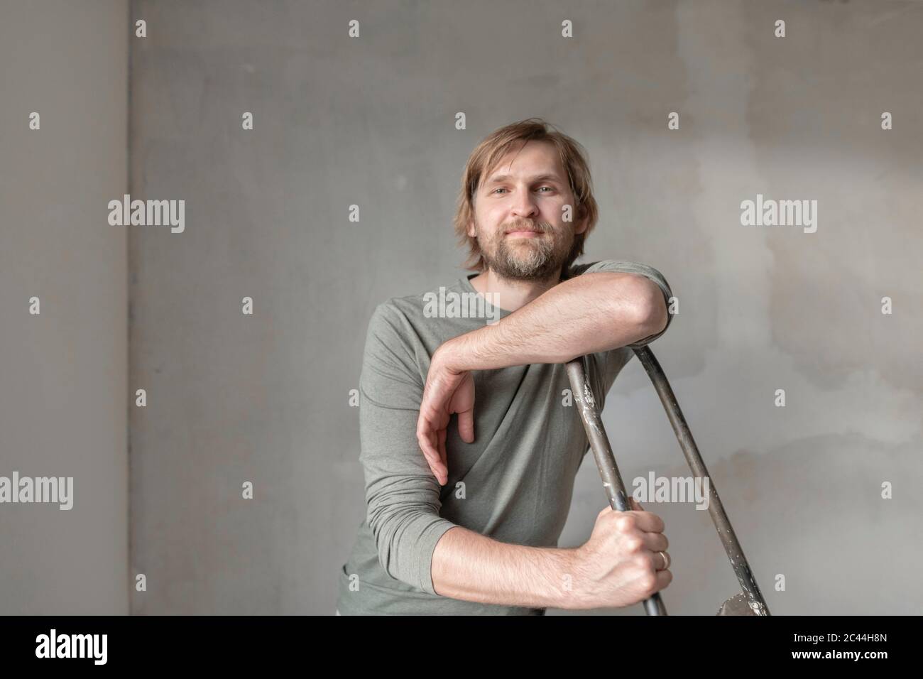 Confident man leaning on ladder during renovation Stock Photo - Alamy