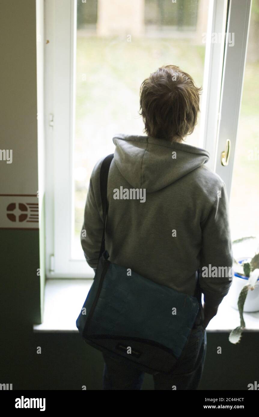 Teenage boy looks out the window Stock Photo - Alamy