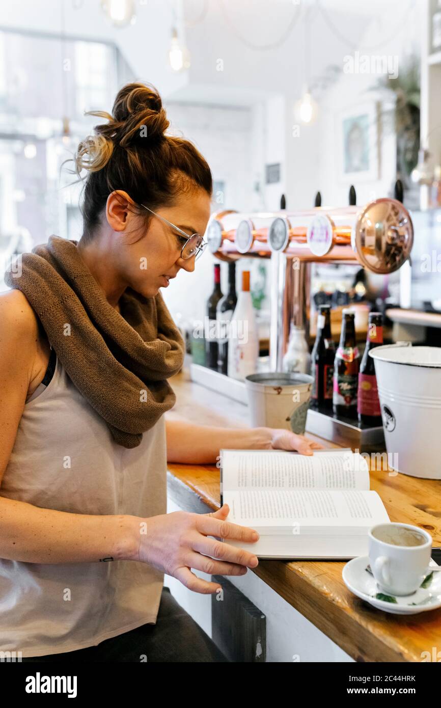 Woman reading book in coffee shop Stock Photo - Alamy