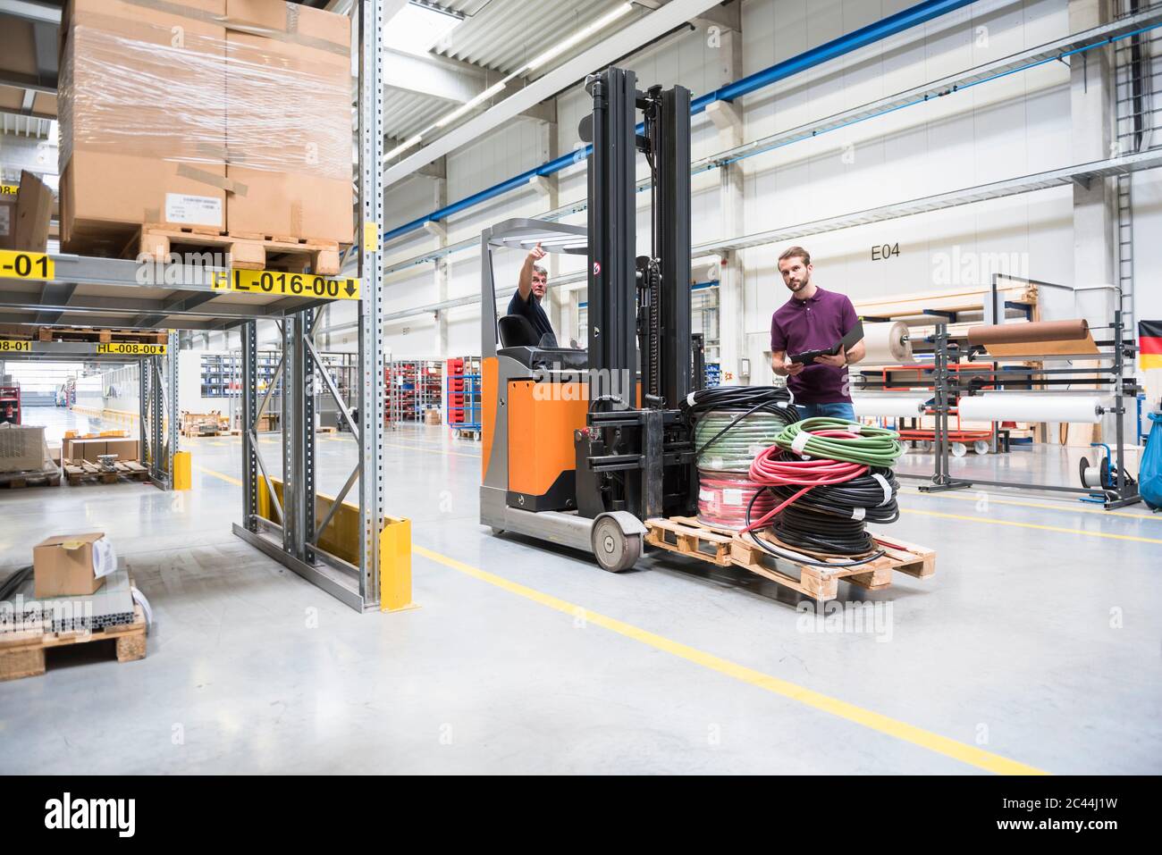 Warehouseman and worker on forklift in high rack warehouse Stock Photo ...