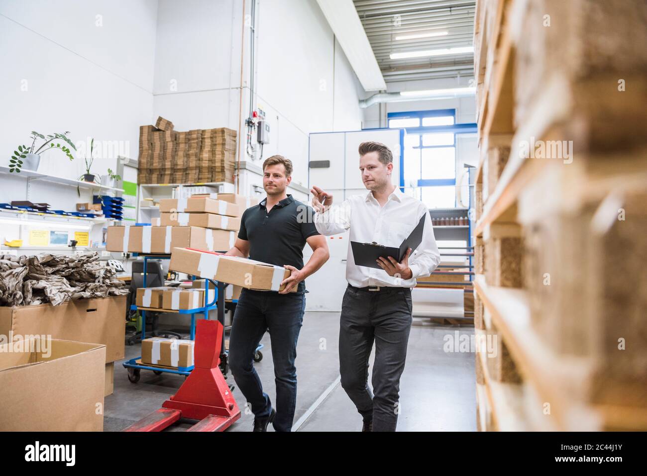 Two men with parcel and clipboard in storehouse of a factory Stock ...