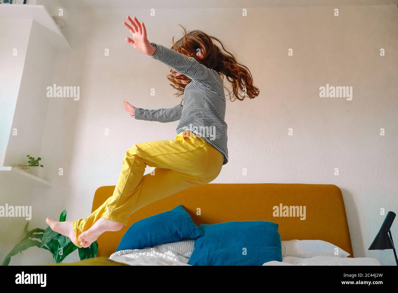 Girl jumping on bed at home Stock Photo - Alamy