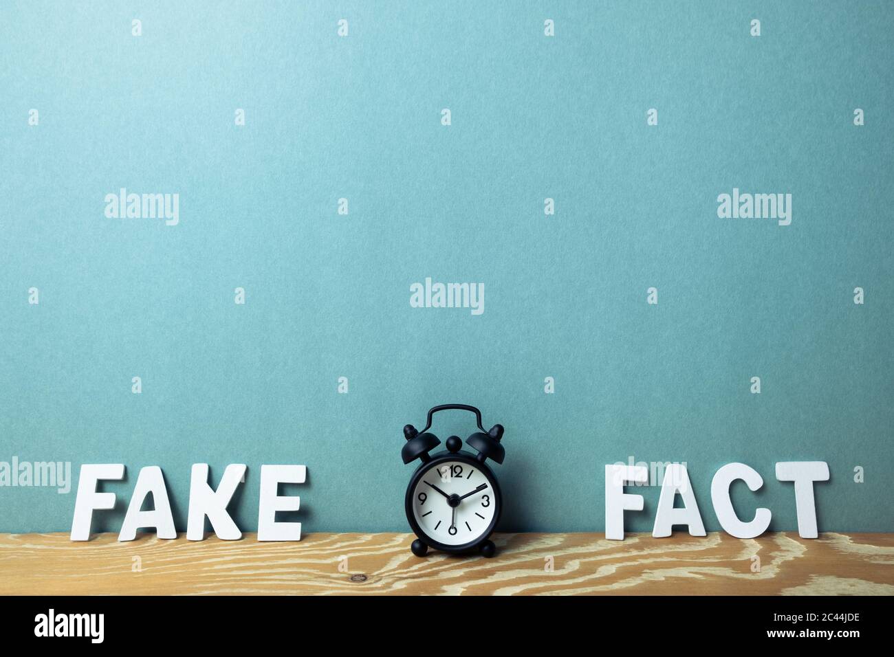 Word Fact or Fake with clock on wooden table. Time will tell the truth ...