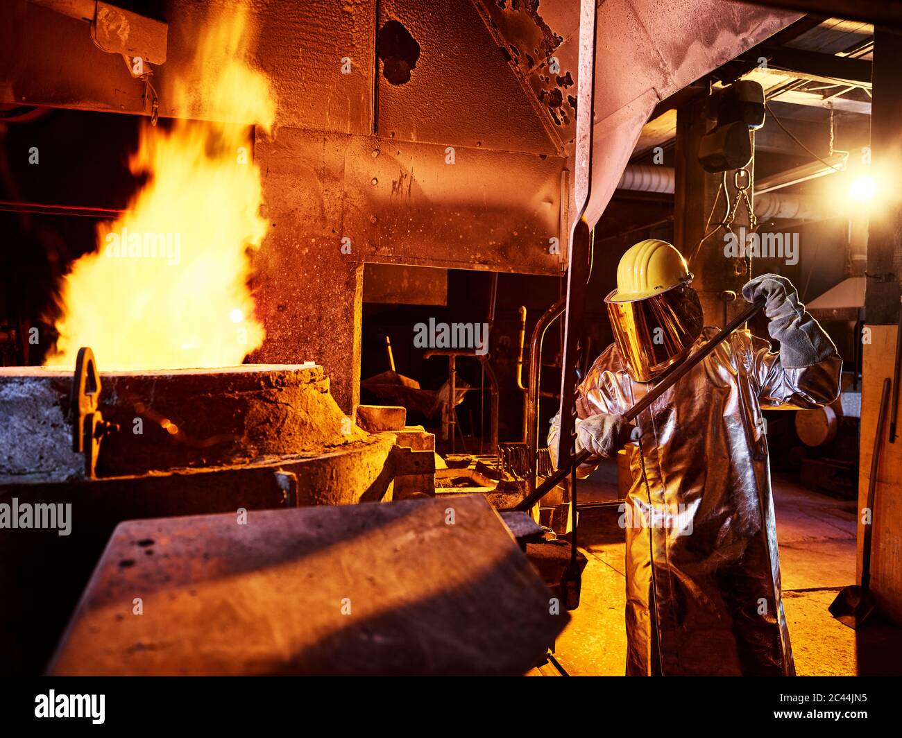 Worker holding metal rod in furnace at foundry Stock Photo - Alamy
