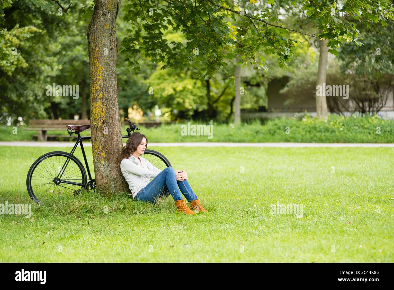 Woman sitting against tree trunk hi-res stock photography and images ...