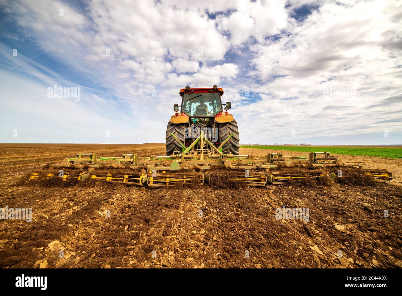 Back view of farmer in tractor plowing field in spring Stock Photo - Alamy