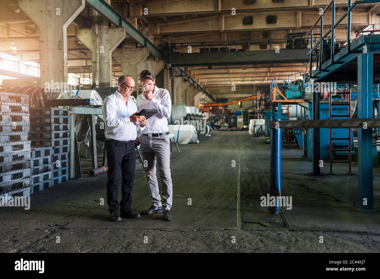 Two businessmen having meeting factory hall hi-res stock photography ...