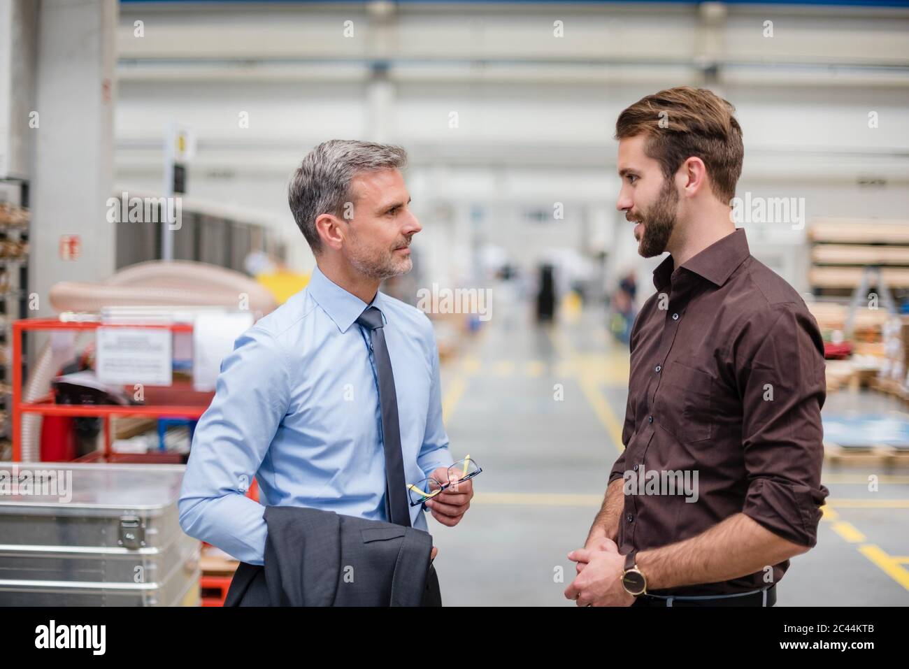 Two businessmen talking in a factory Stock Photo - Alamy