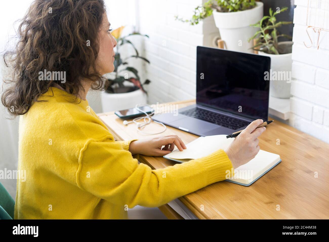 Woman working at desk in home office taking notes Stock Photo - Alamy