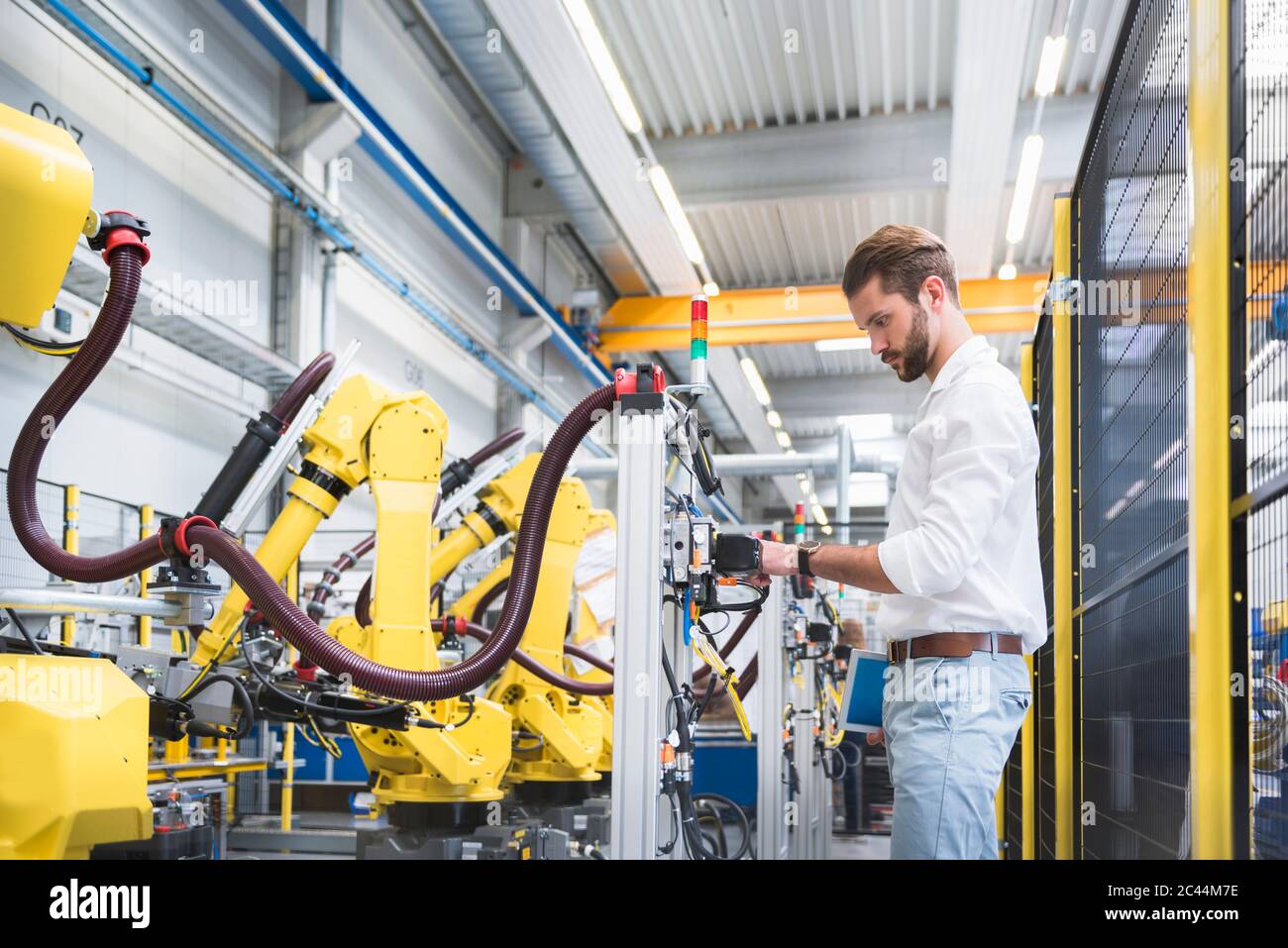 Side view of confident robotics expert examining machinery in factory ...