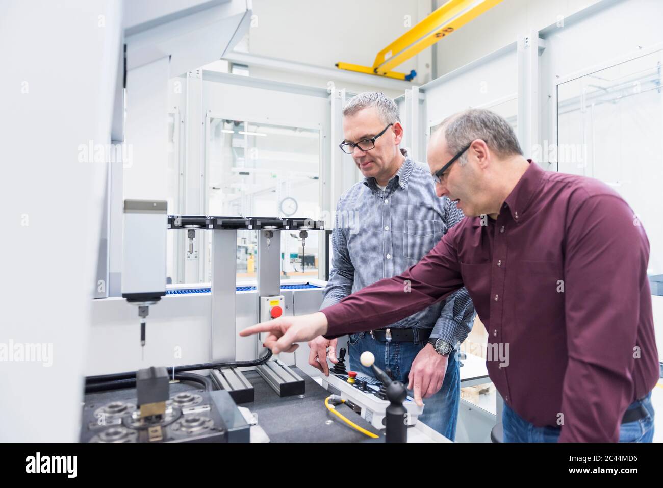 Two businessmen having a discussion at a machine in a factory Stock ...