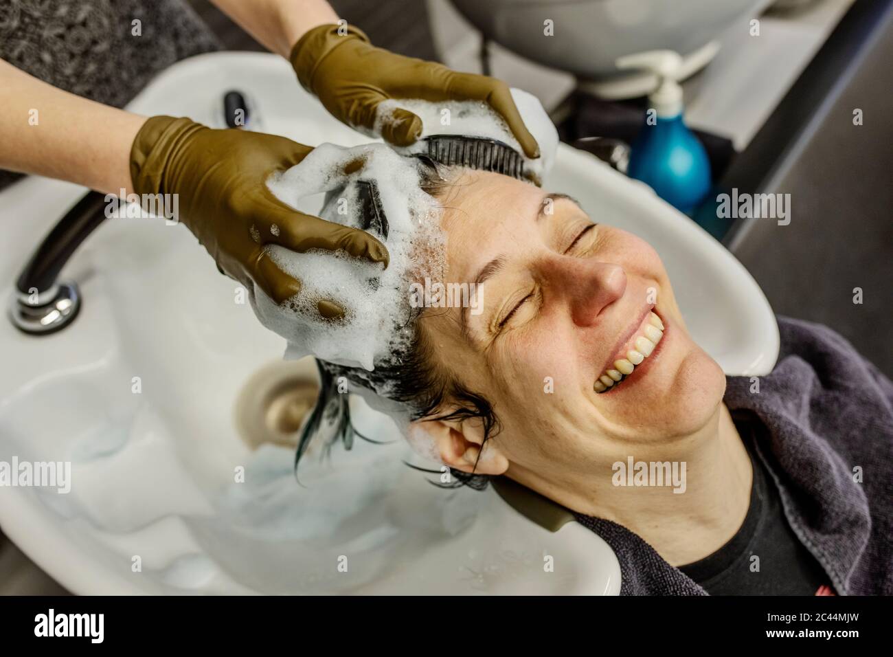 Woman in hair salon getting hair washed with brushes Stock Photo - Alamy