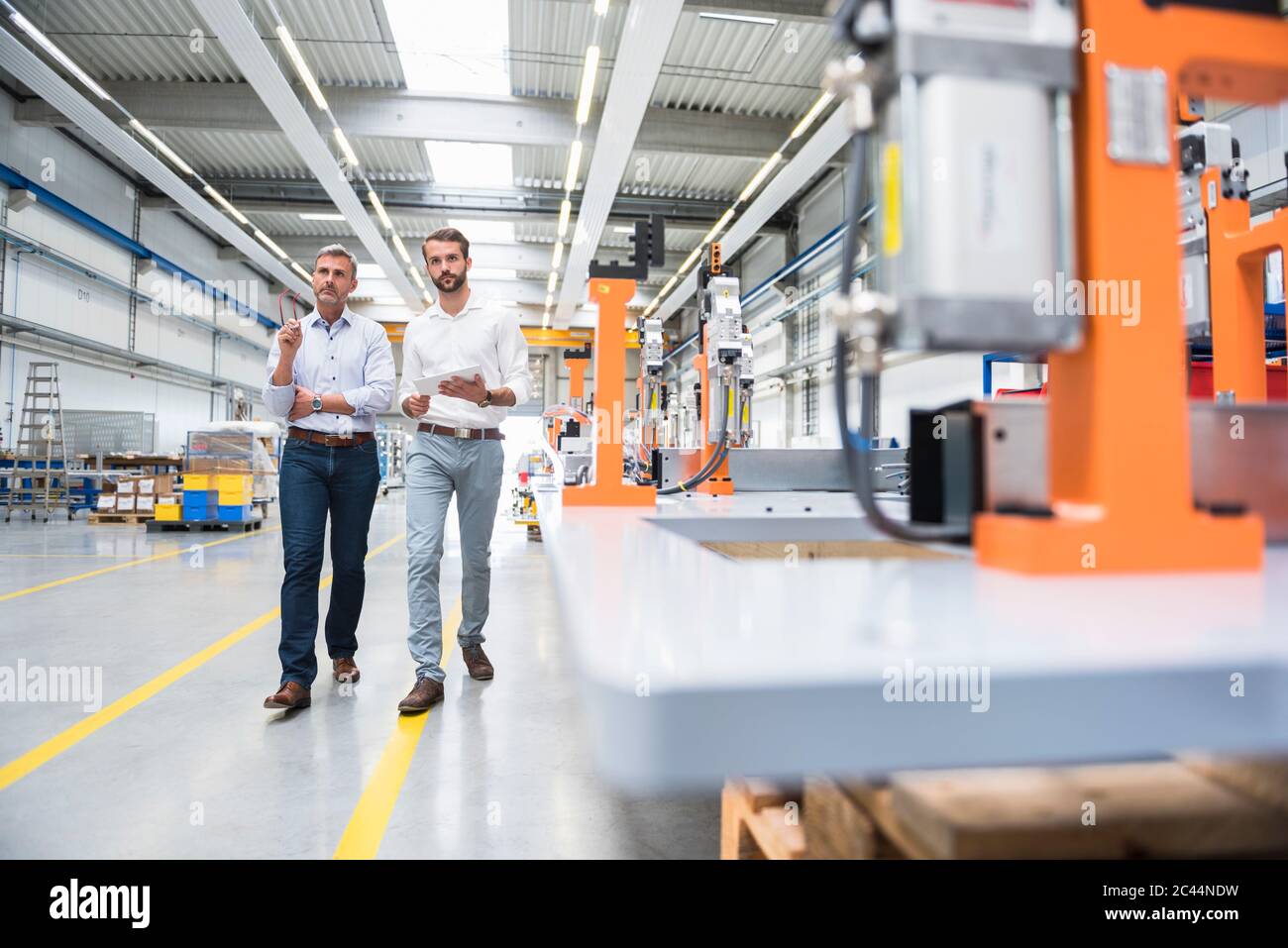 Two men walking and talking on factory shop floor Stock Photo - Alamy