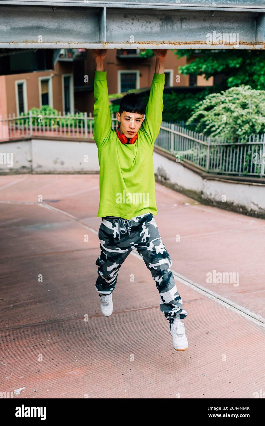 Young man hanging on metallic built structure Stock Photo - Alamy