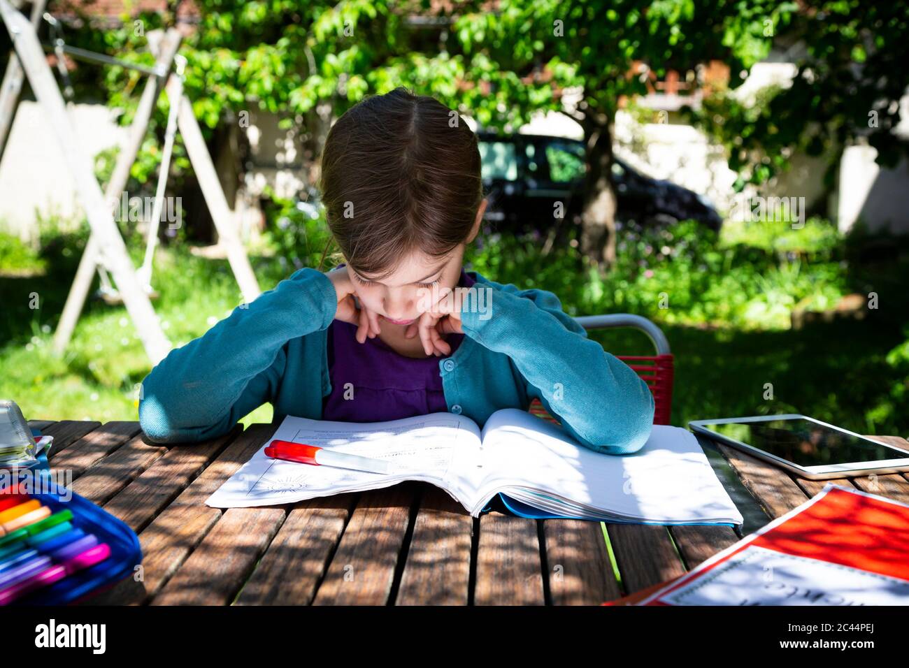 Girl sitting at garden table doing homework Stock Photo - Alamy