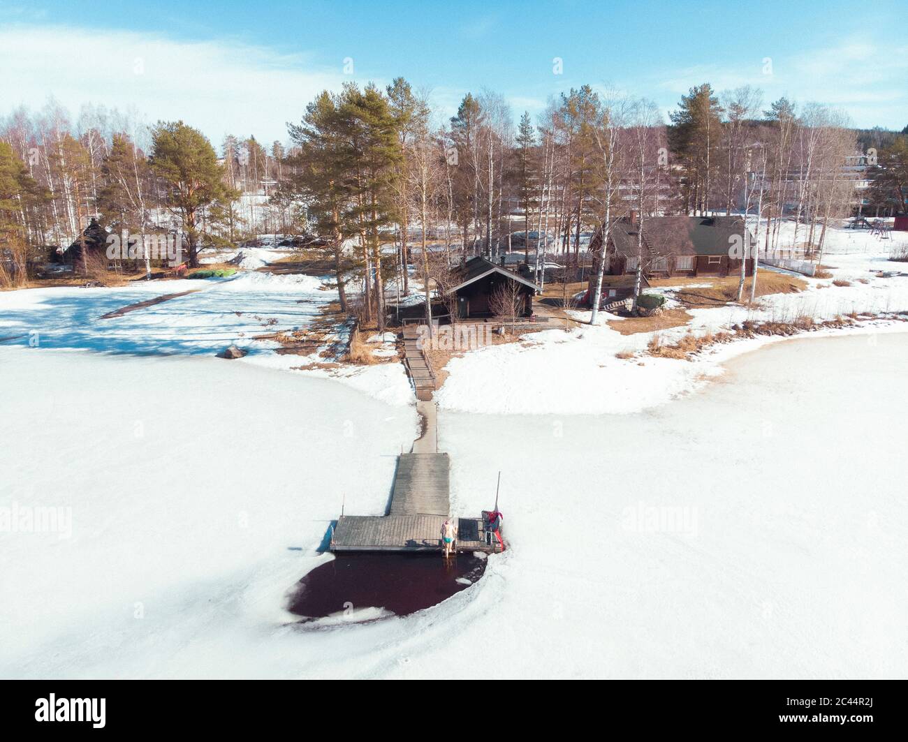 Finland, Kuopio, high angle view of woman swimming in frozen lake in ...