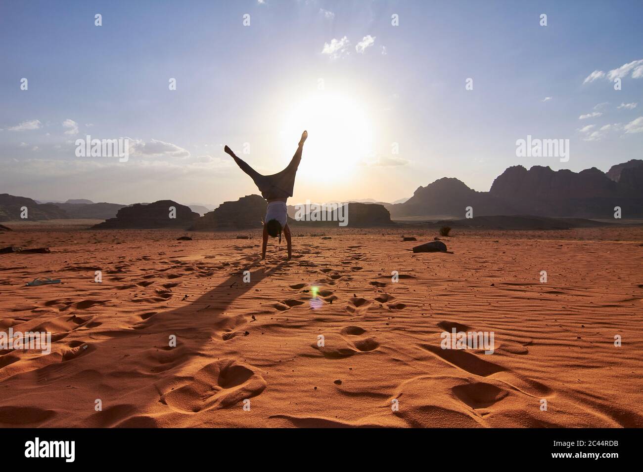 Woman doing a handstand on the red sand desert in Wadi Rum desert ...