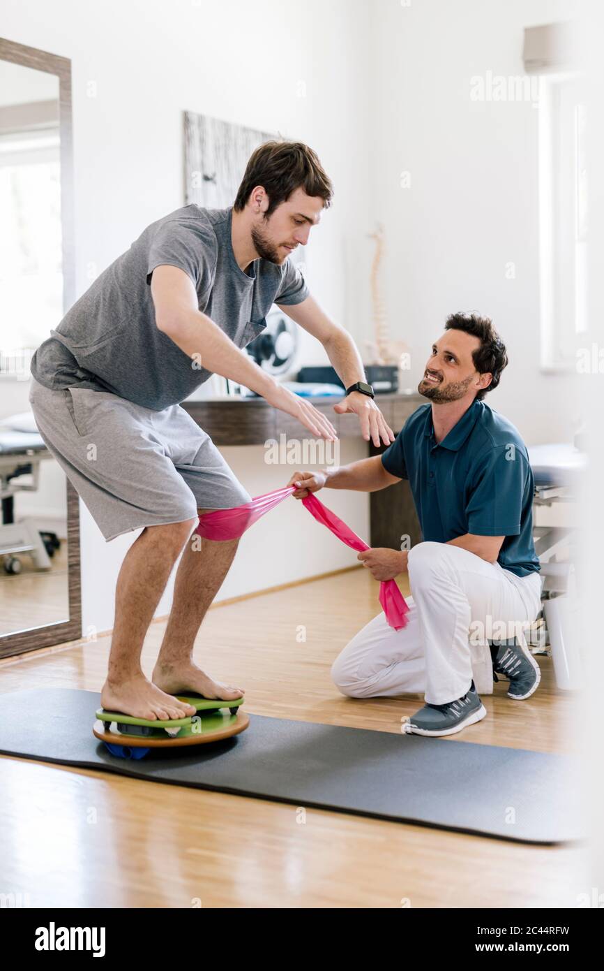 Physiotherapist assisting patient, practicing on balance trainer Stock ...