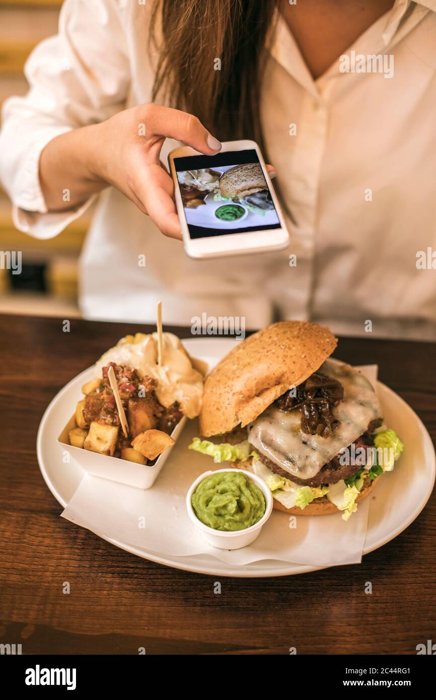 Midsection of woman photographing fresh meal served in plate on table ...