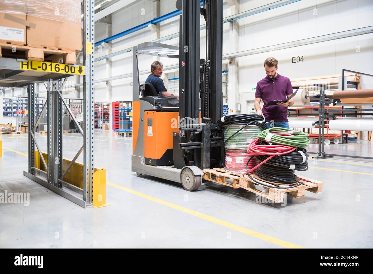 Warehouseman and worker on forklift in high rack warehouse Stock Photo ...