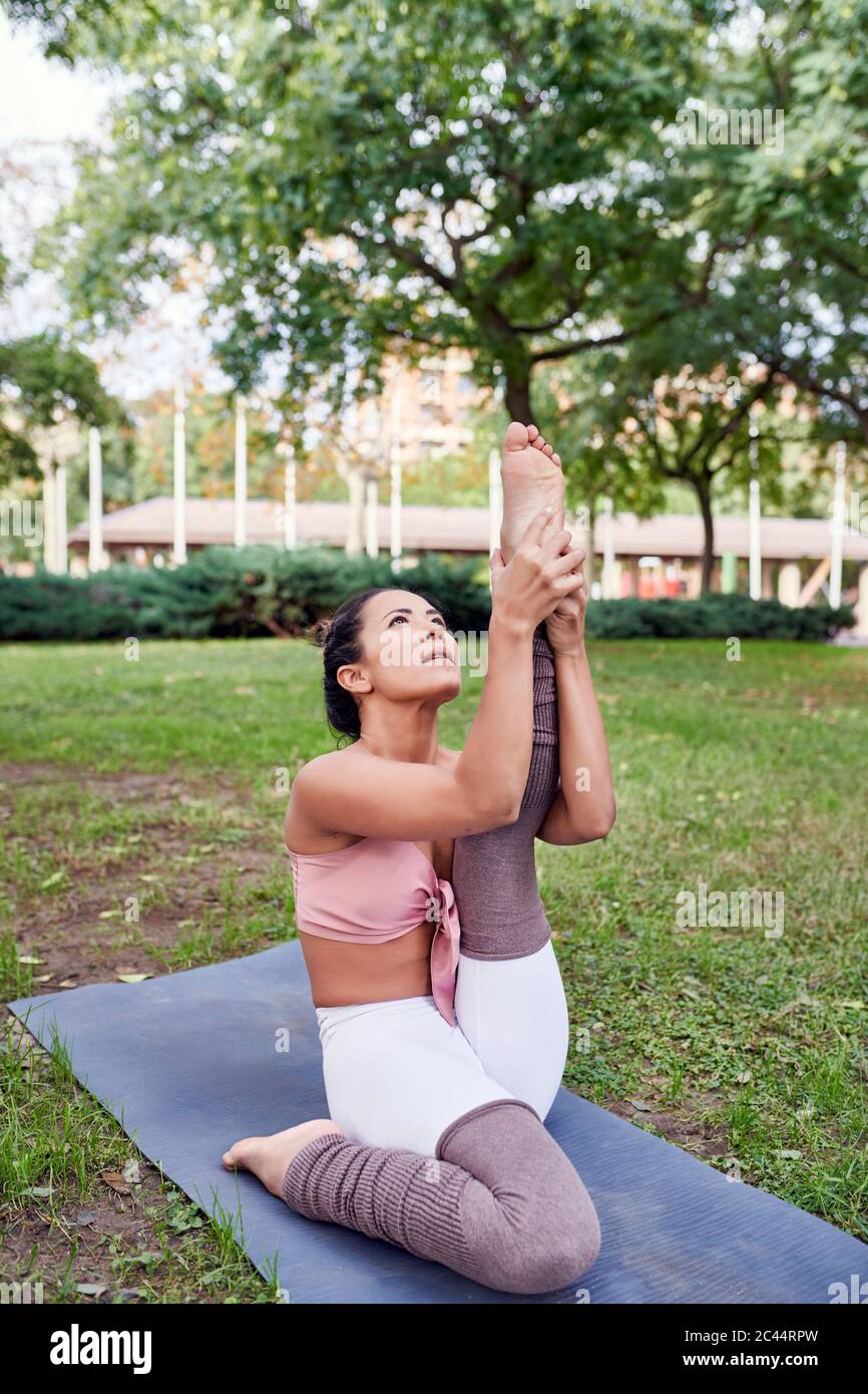 Mid adult woman practising yoga on mat park hi-res stock photography ...