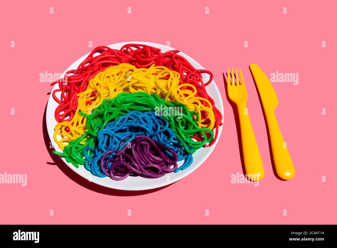 Plate of rainbow-colored spaghetti against pink background Stock Photo ...