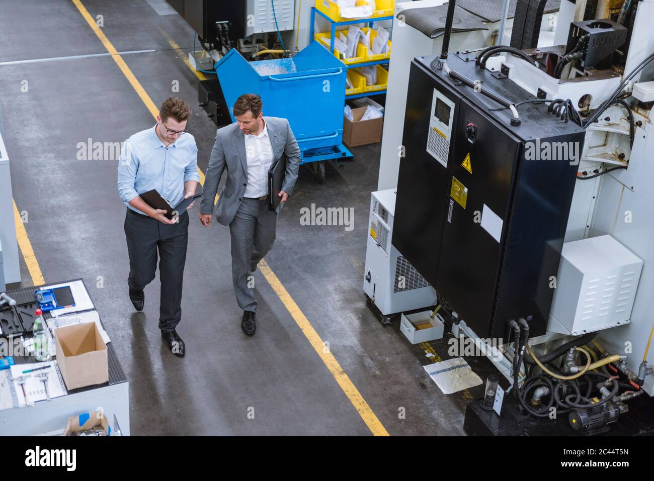 Two businessmen with clipboard walking and talking in factory Stock ...