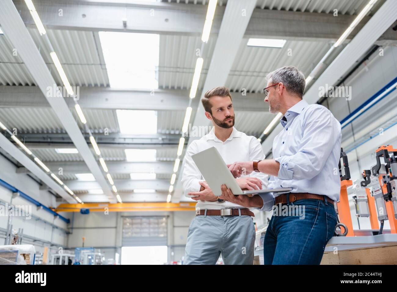 Two men using laptop on factory shop floor Stock Photo - Alamy