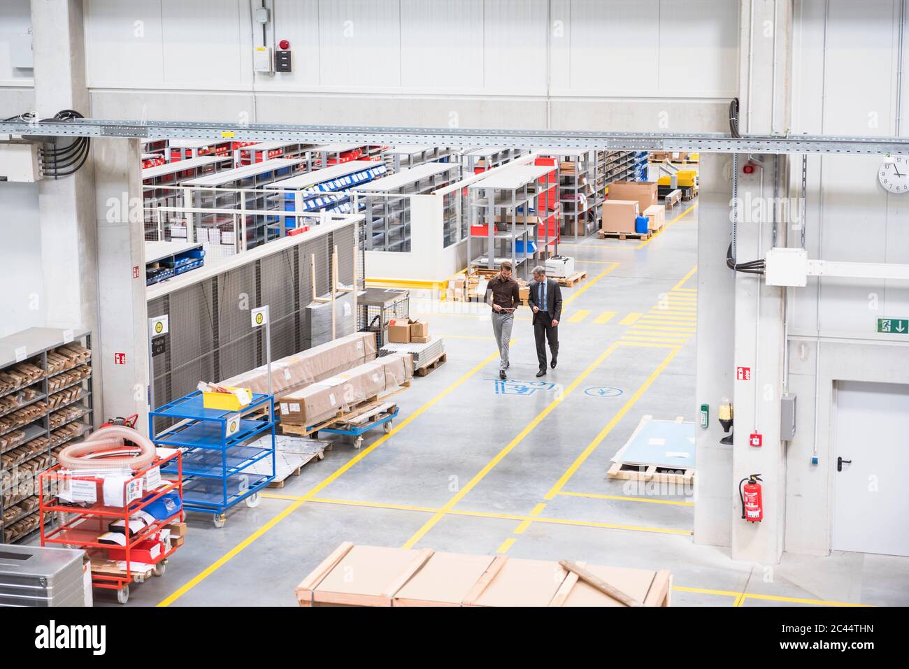 Two businessmen walking on factory shop floor Stock Photo - Alamy