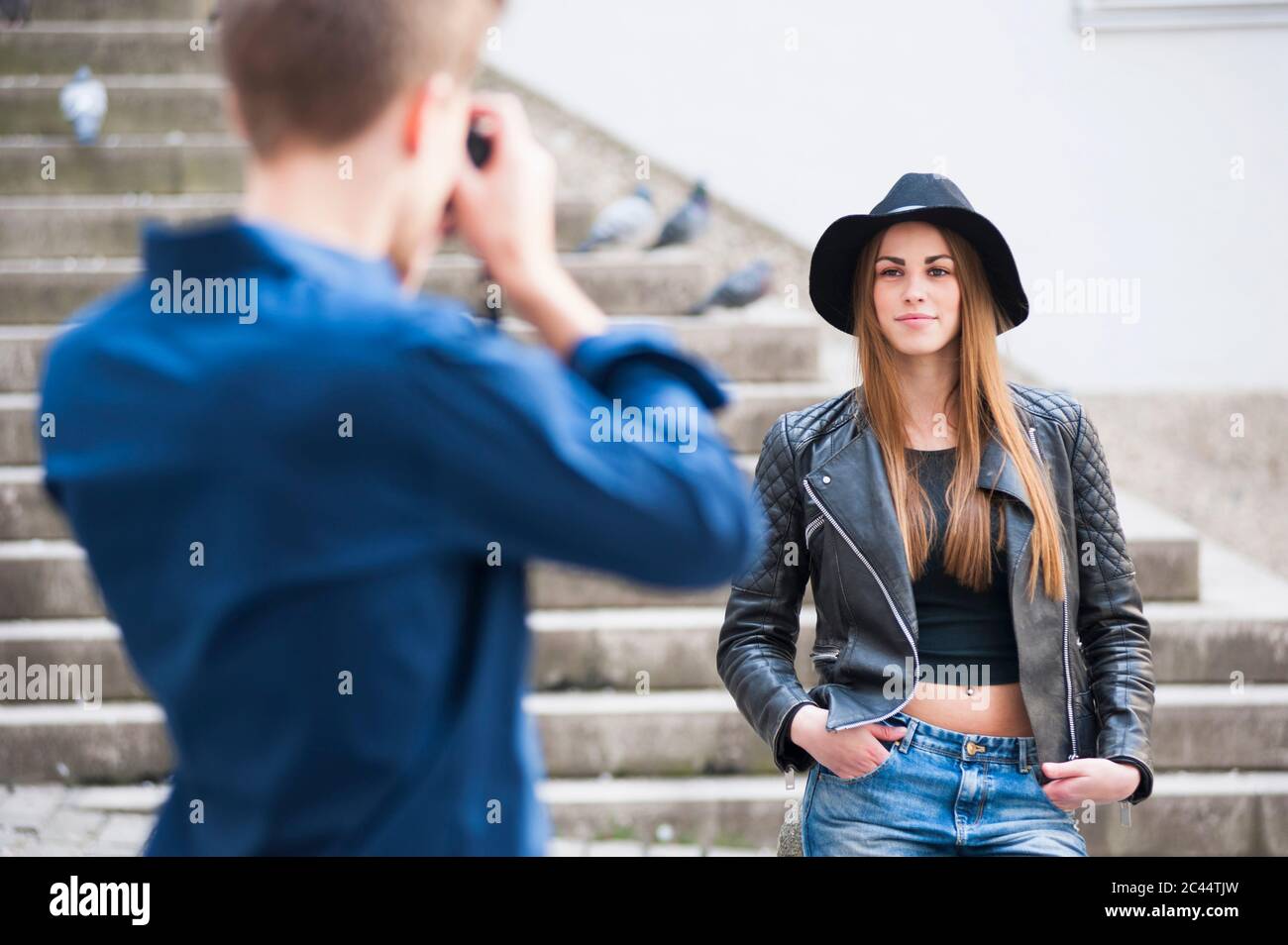 Man photographing fashionable woman through camera on steps in city ...