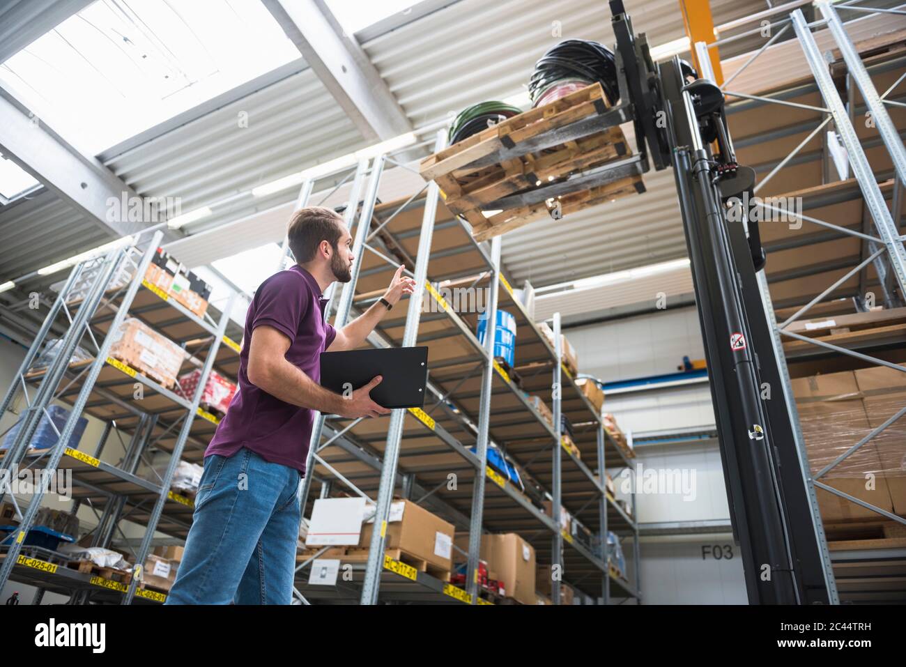 Warehouseman and goods on forklift in high rack warehouse Stock Photo ...