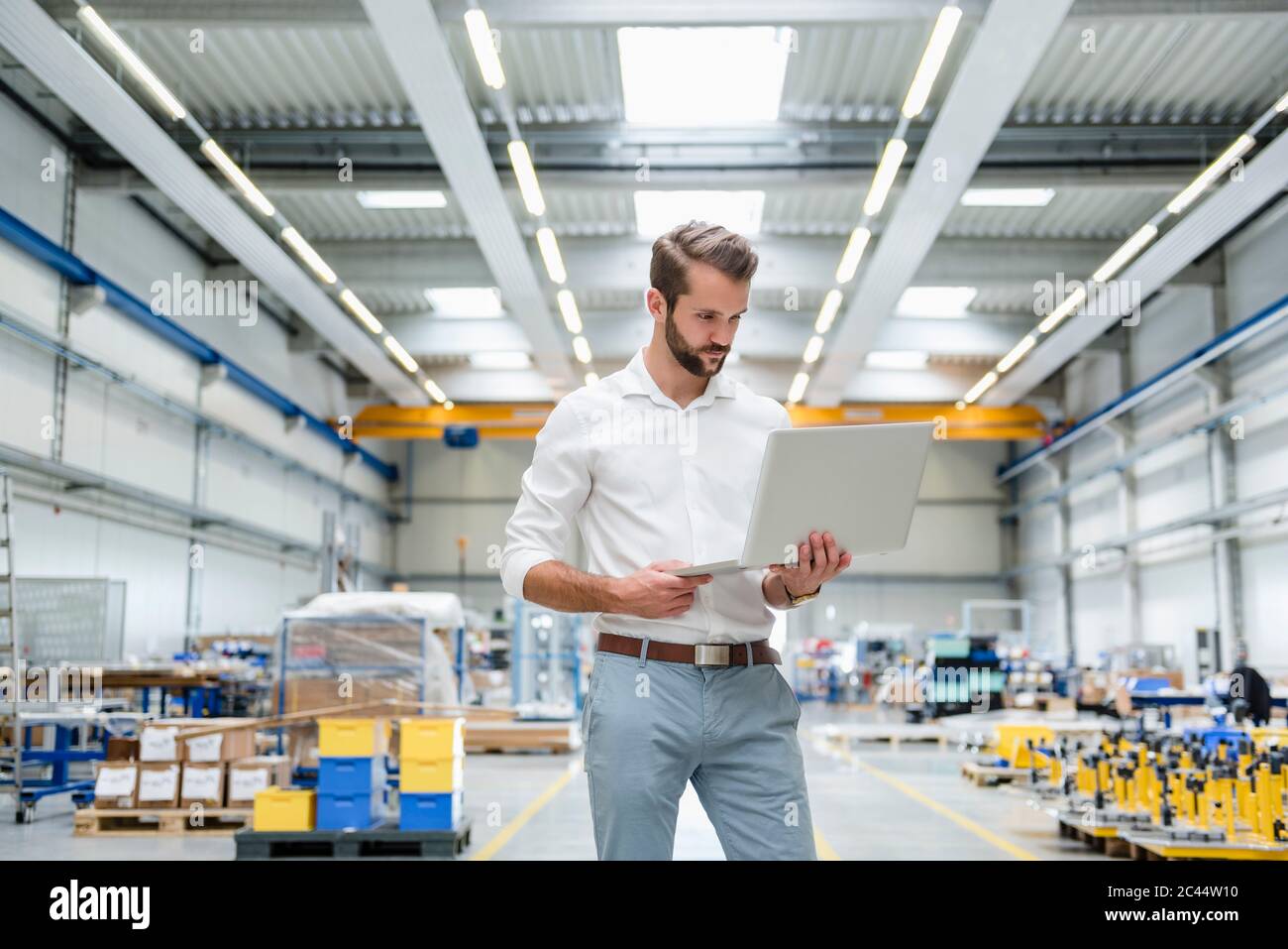Young man using laptop on factory shop floor Stock Photo - Alamy