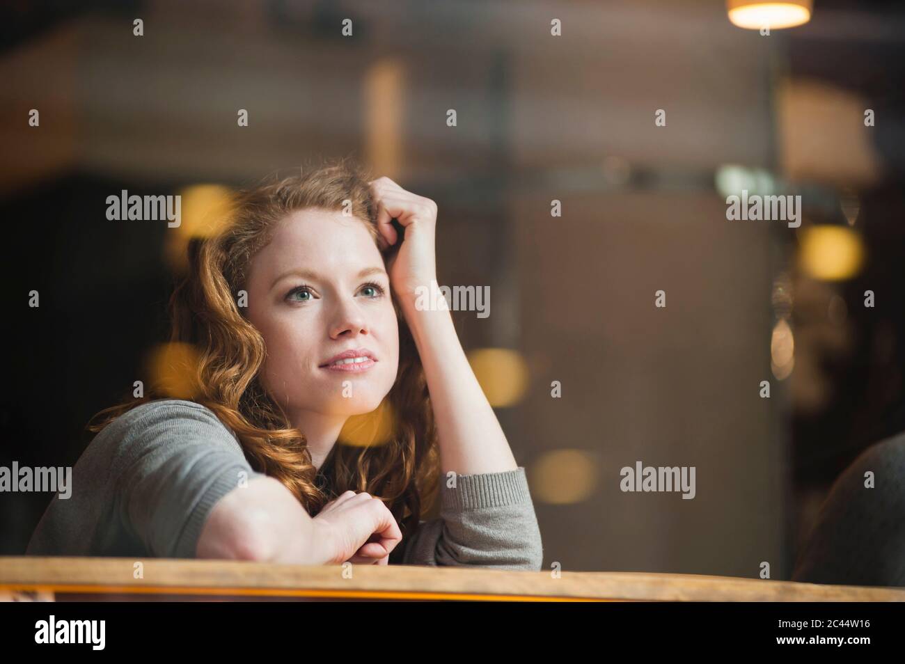 Thoughtful woman leaning on table seen through glass window in coffee ...