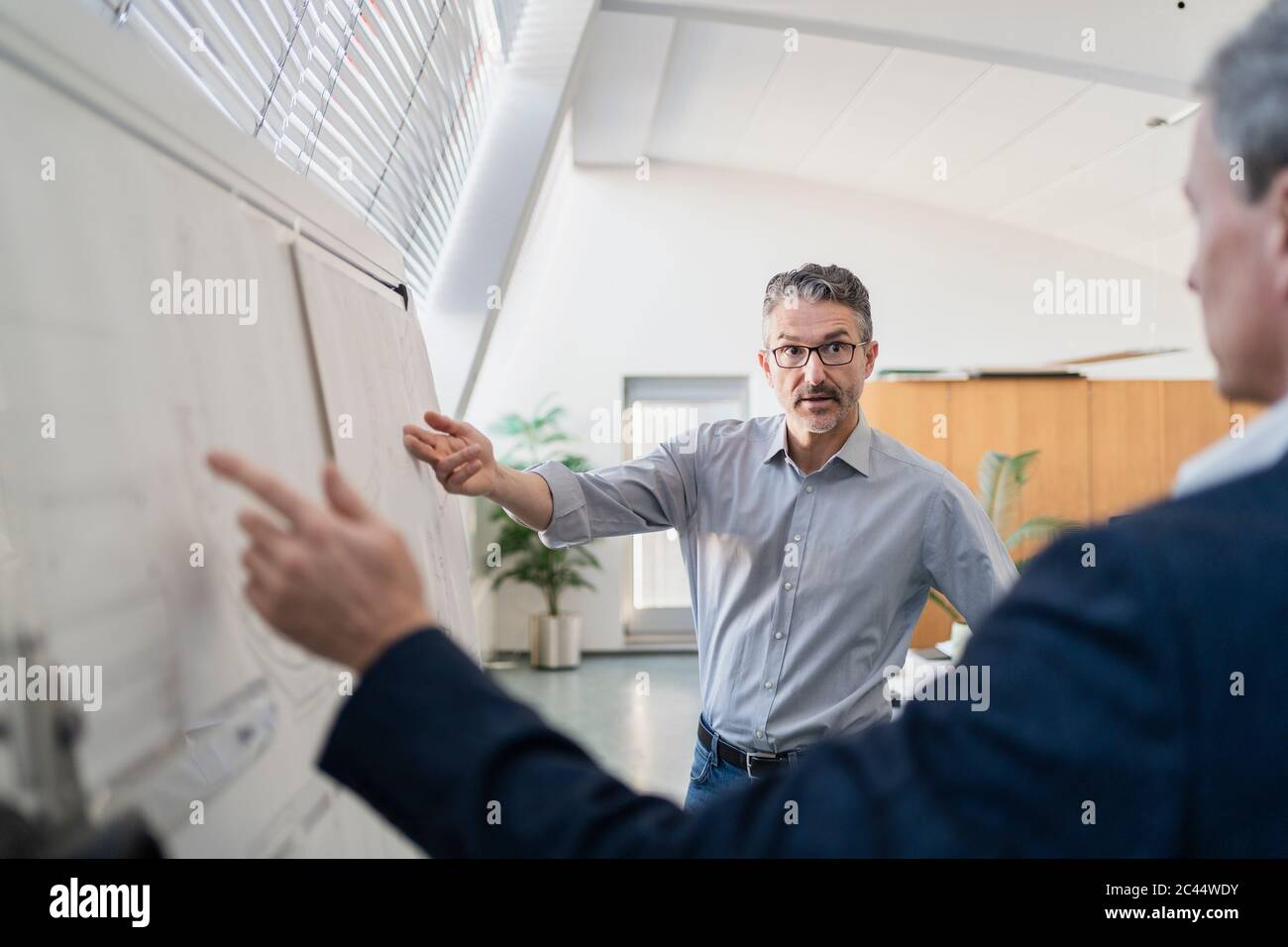 Confident mature male professional pointing while explaining strategy ...