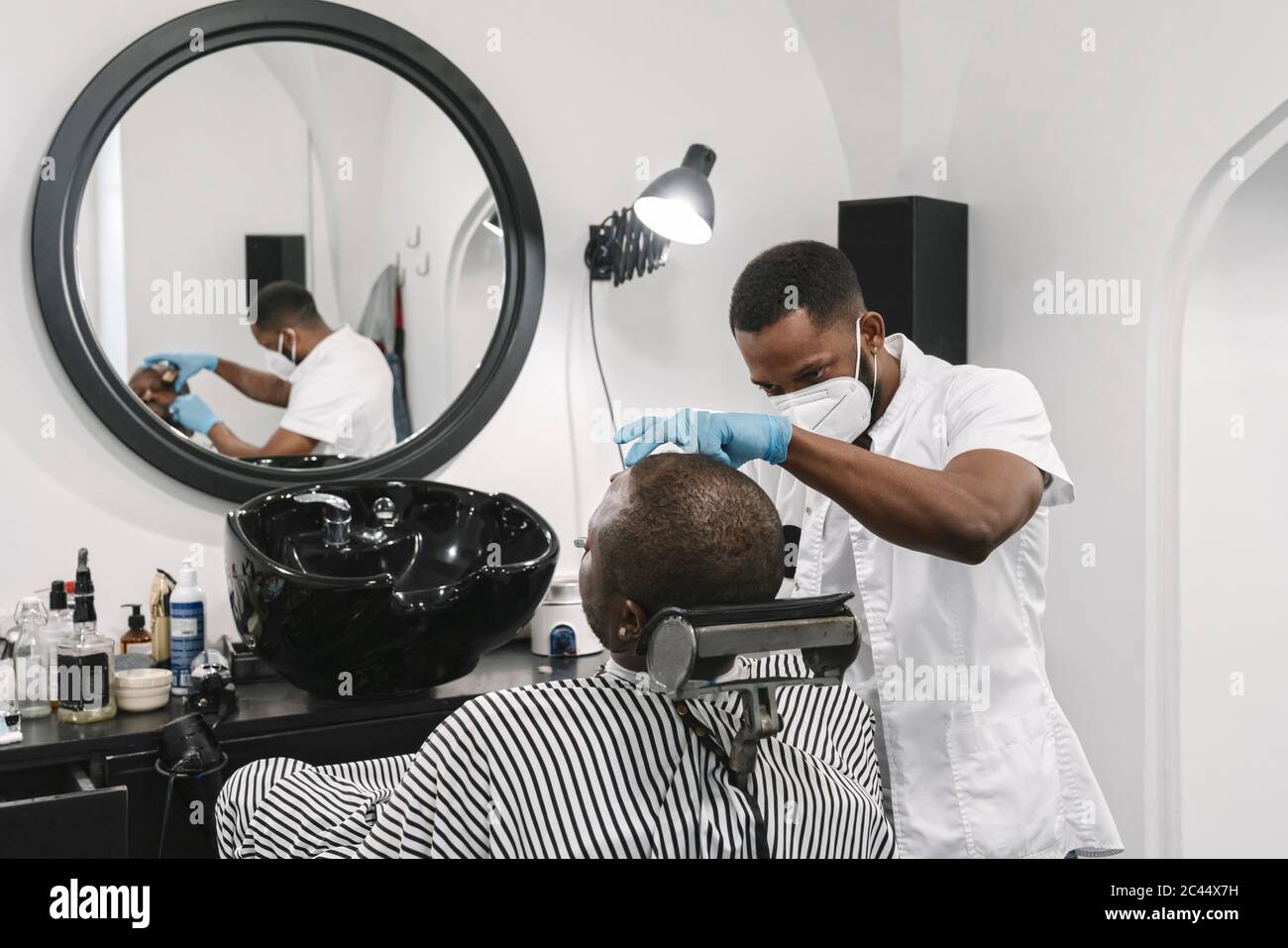 Barber wearing surgical mask and gloves cutting hair of customer Stock ...