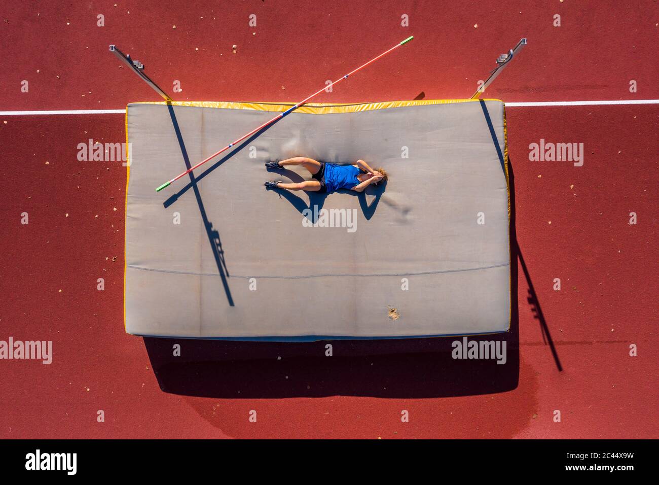Female athlete lying on mat after failed high jump hi-res stock ...
