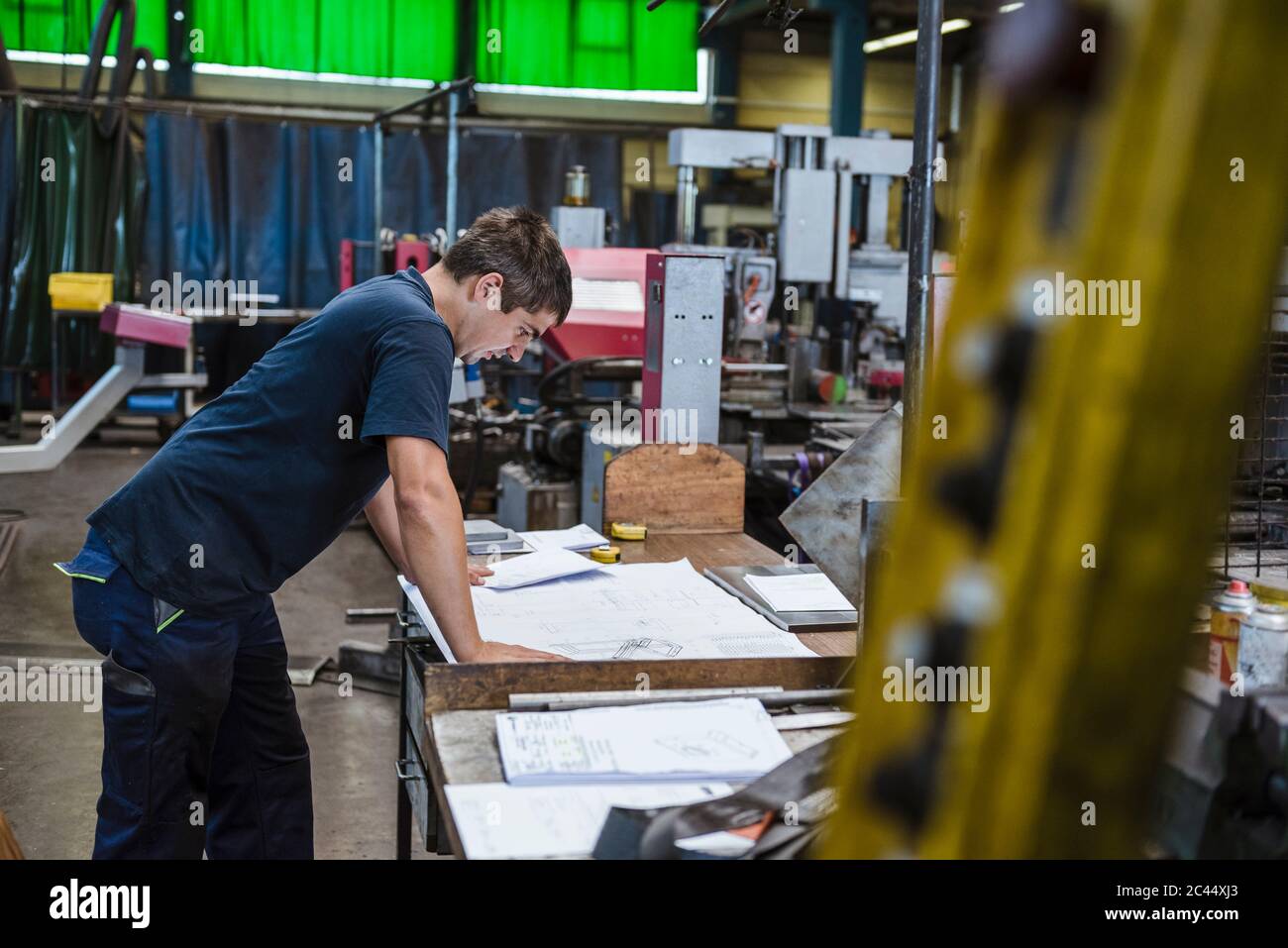Man studying a plan on workbench in a factory Stock Photo - Alamy