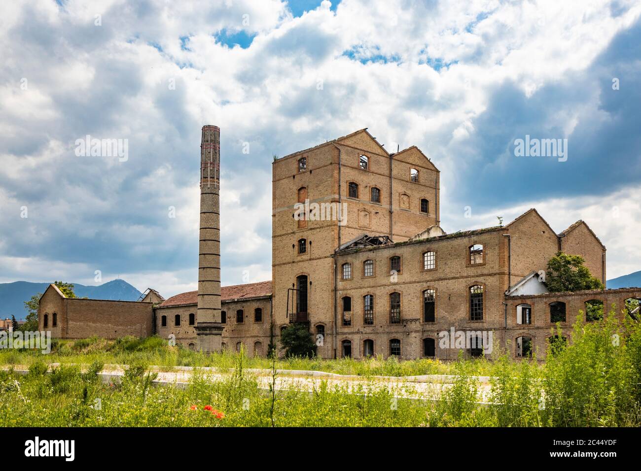 An old disused factory, abandoned and in ruins, with a smashed roof and ...