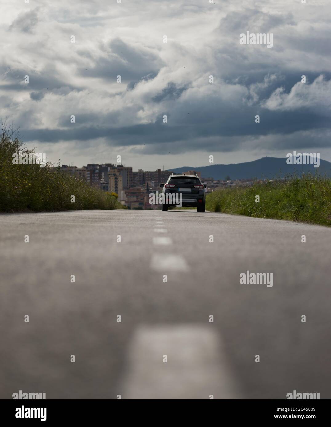 SUV car on the road with buildings and mountains in the background ...