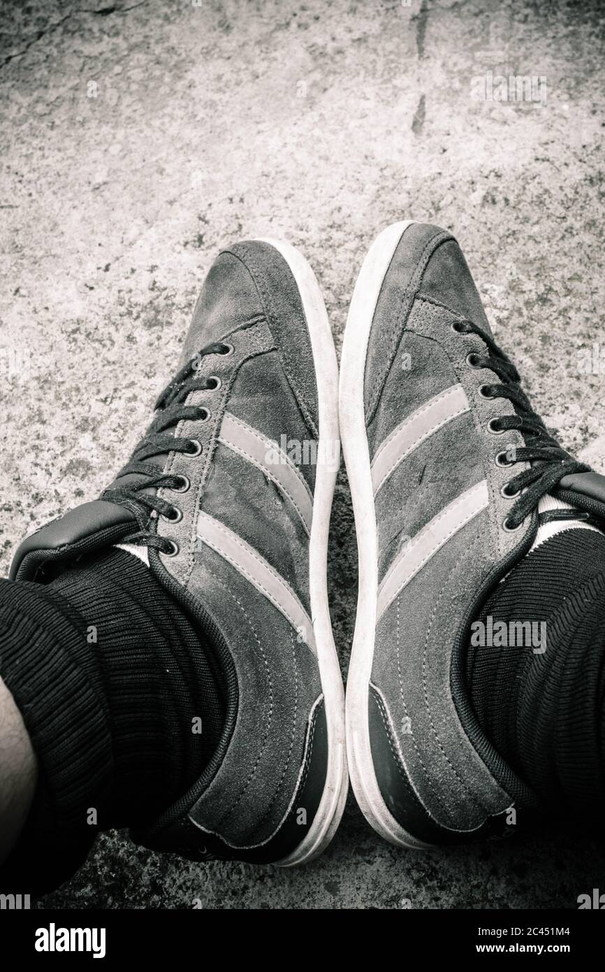 Vertical grayscale shot of a male wearing sneakers with stripes Stock ...