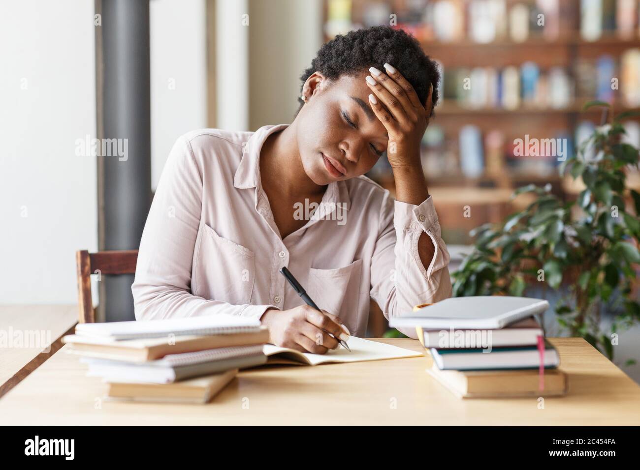 Tired African American girl studying for hard exam at city cafe Stock ...