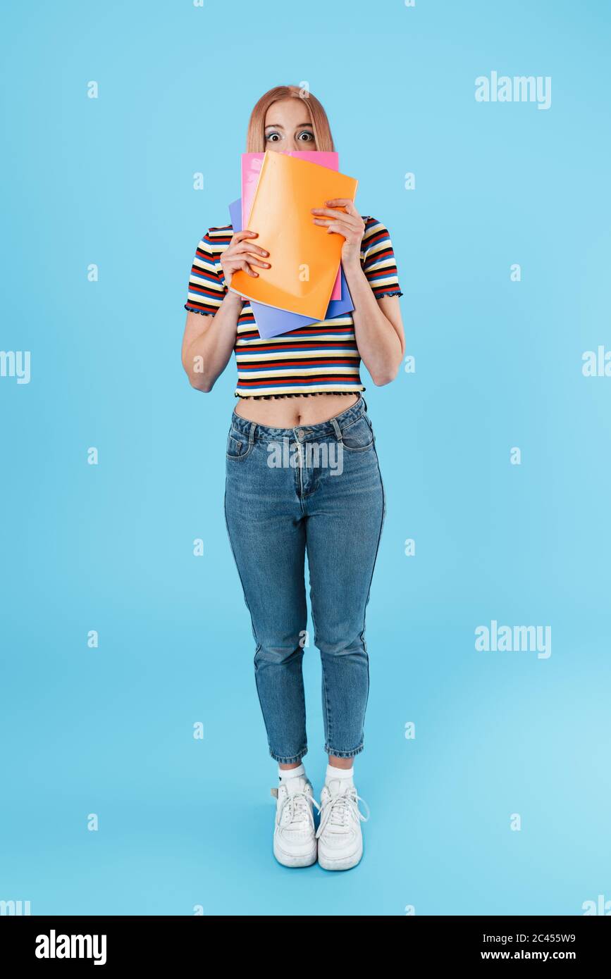 Image of scared caucasian girl covering her face with exercise books ...